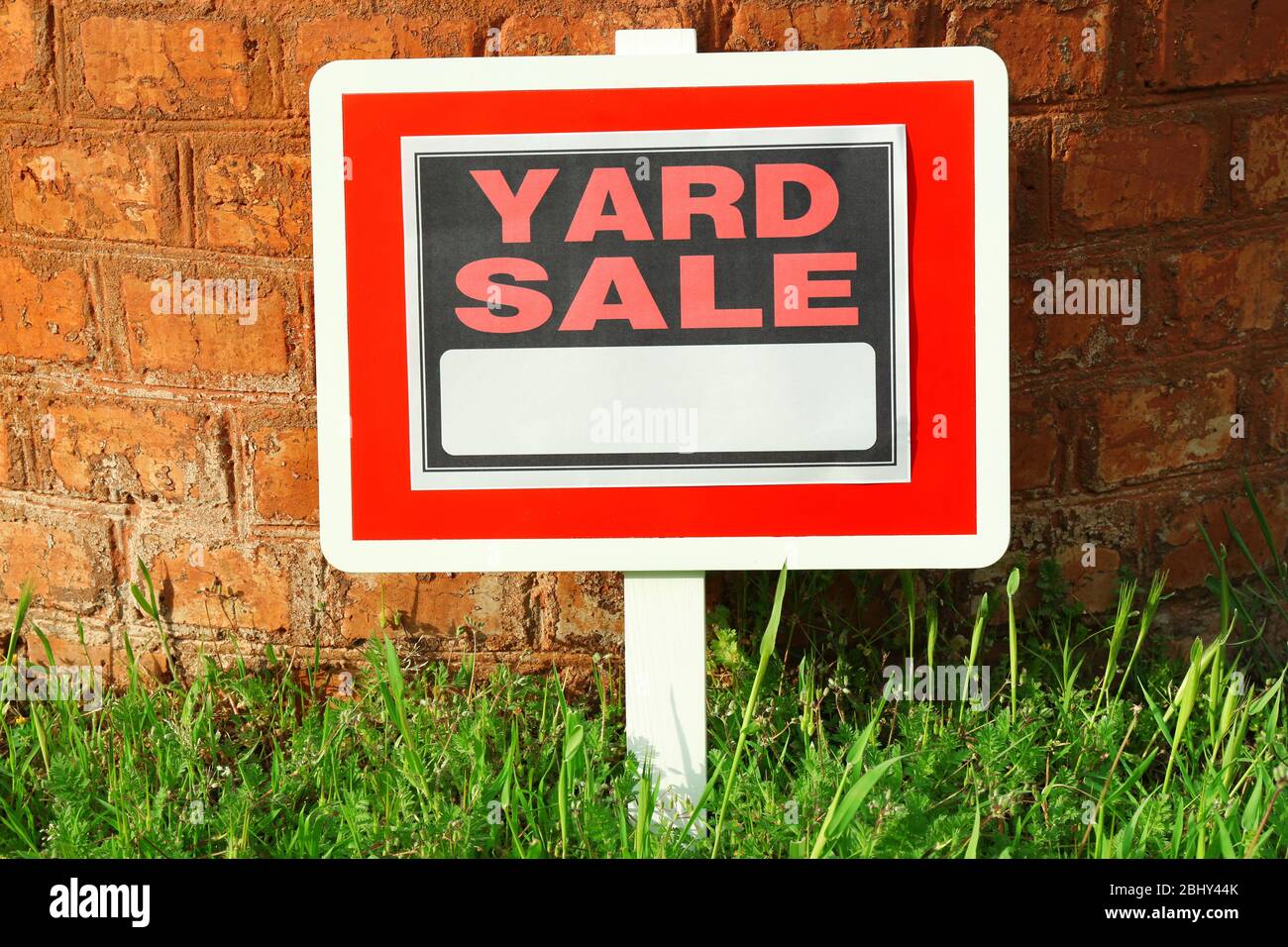 Wooden Yard Sale sign in green grass on red brick wall background Stock ...