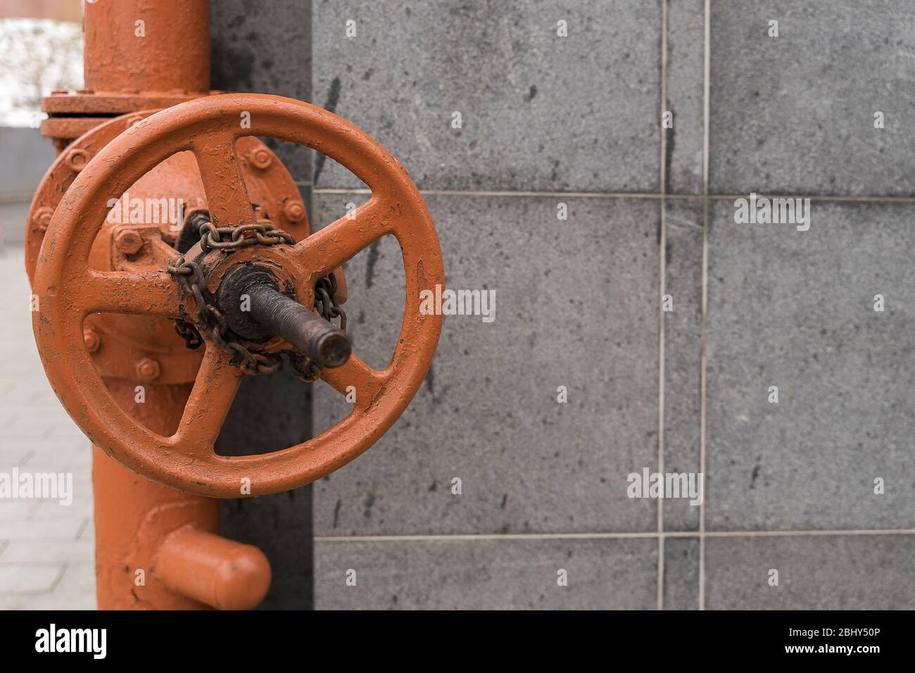 large pipe valve against a gray brick wall Stock Photo - Alamy