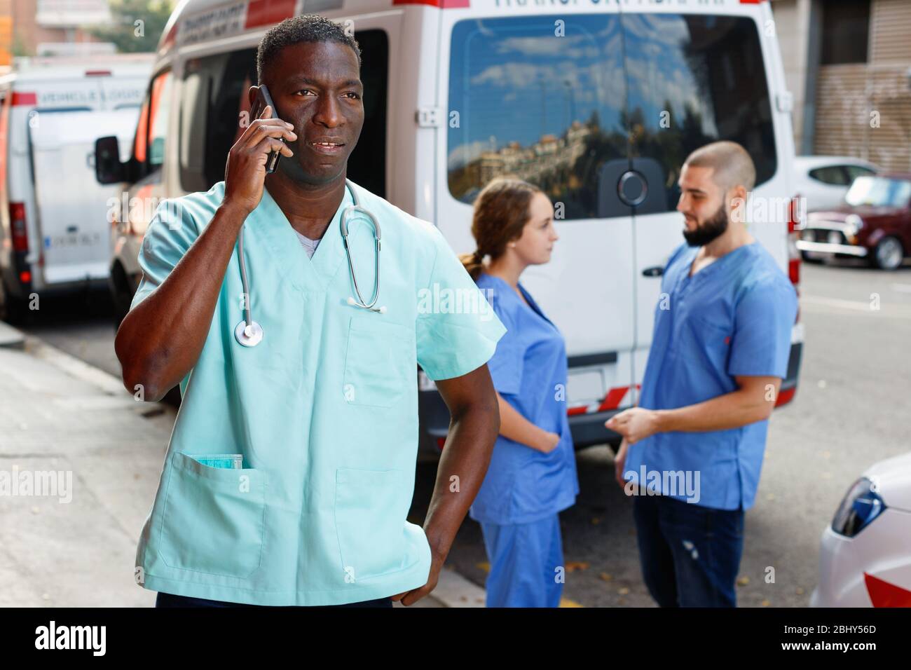 Positive friendly smiling efficient paramedics with first aid kit going ...