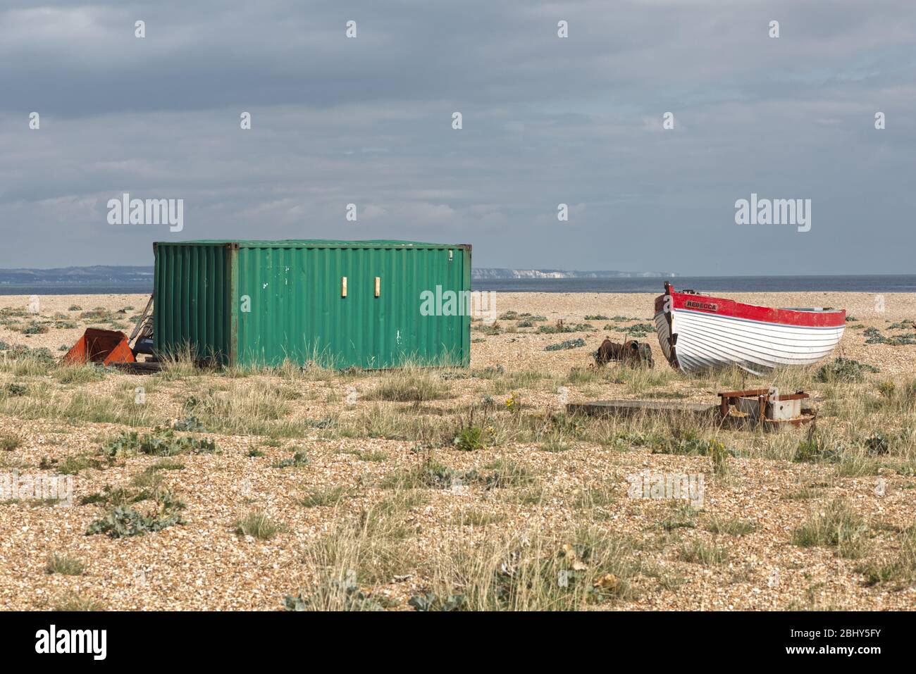 shipping container and wooden boat on a shingle beach Stock Photo - Alamy