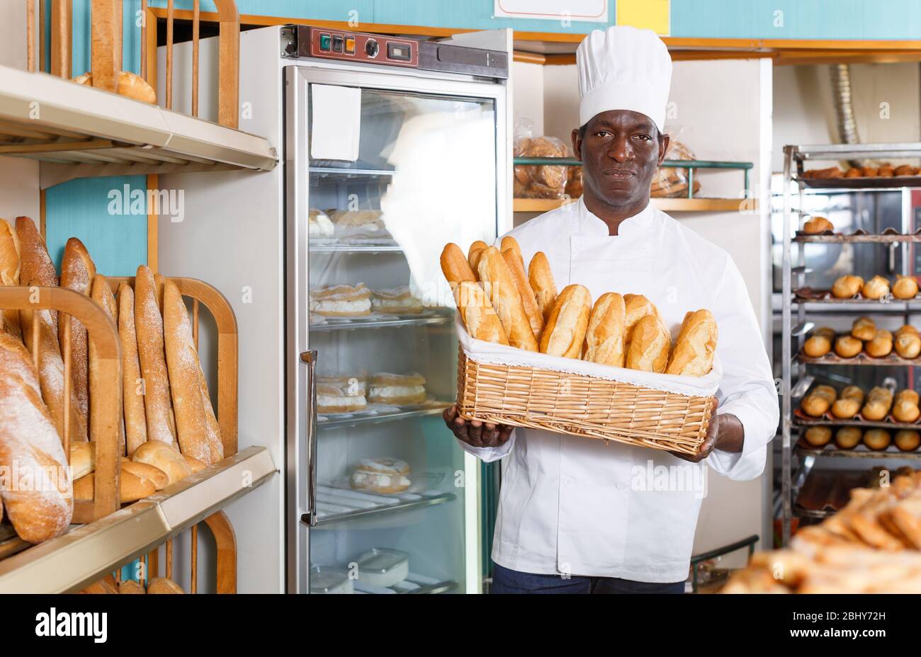 African American bakery chef in white uniform holding wicker basket ...