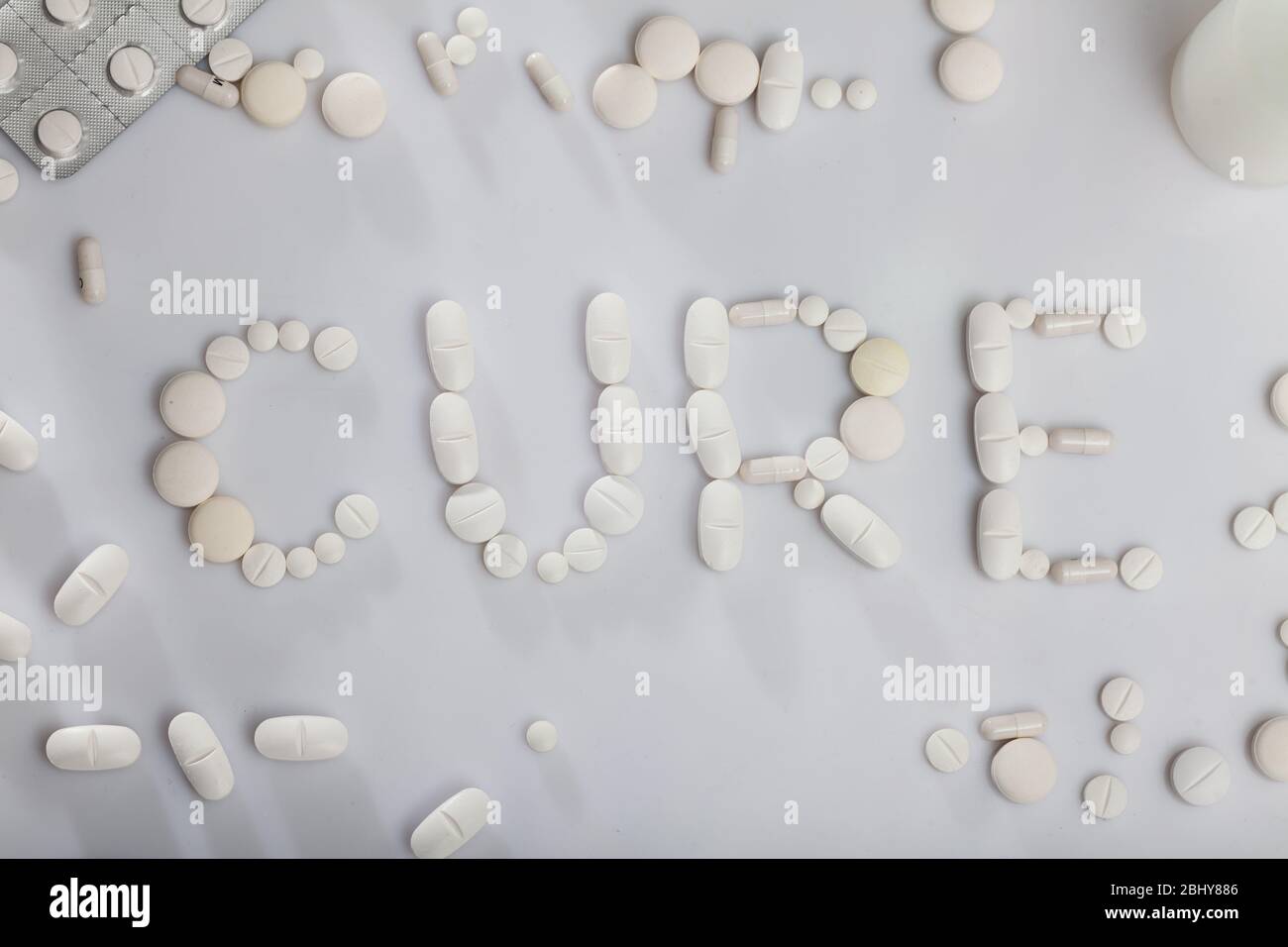Various pills and capsules formed word CURE on white background ...