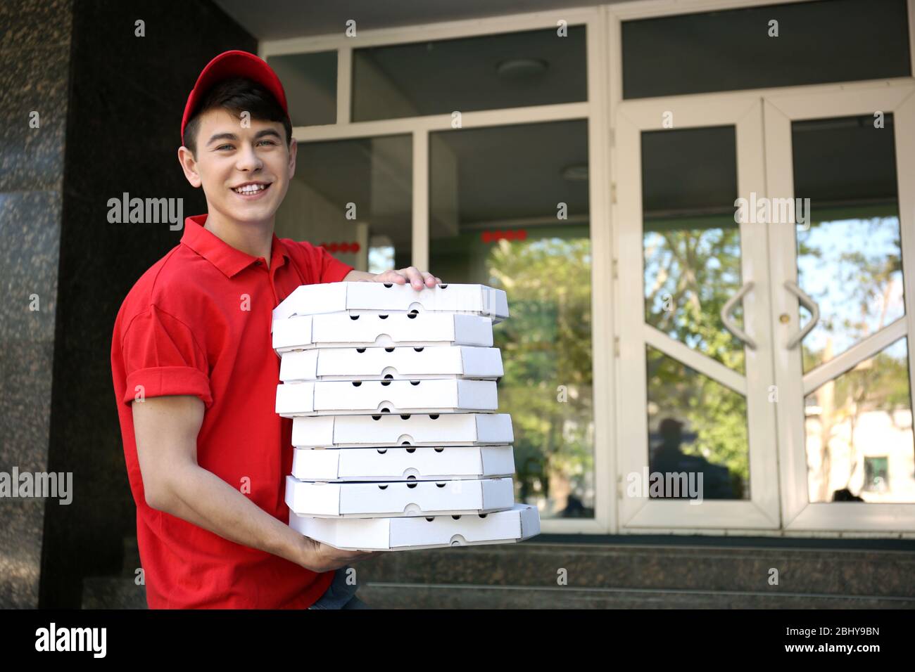 Young man delivering pizza box near house Stock Photo - Alamy