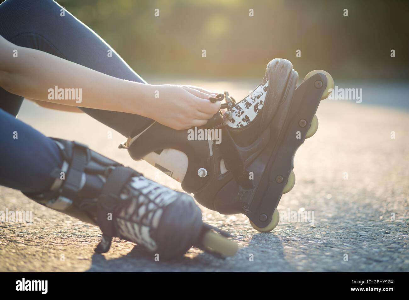 Young woman wearing, preparing her inline skates fot skating, sport ...