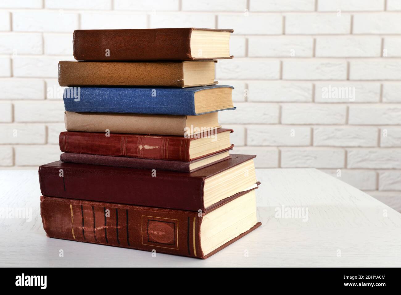 Heap of old books on brick wall background Stock Photo - Alamy