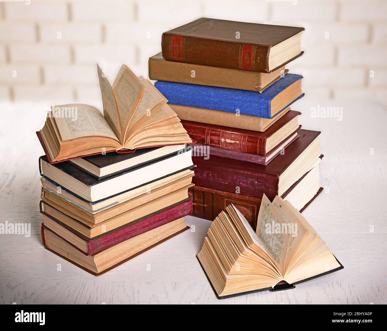 Heap of old books on brick wall background Stock Photo - Alamy