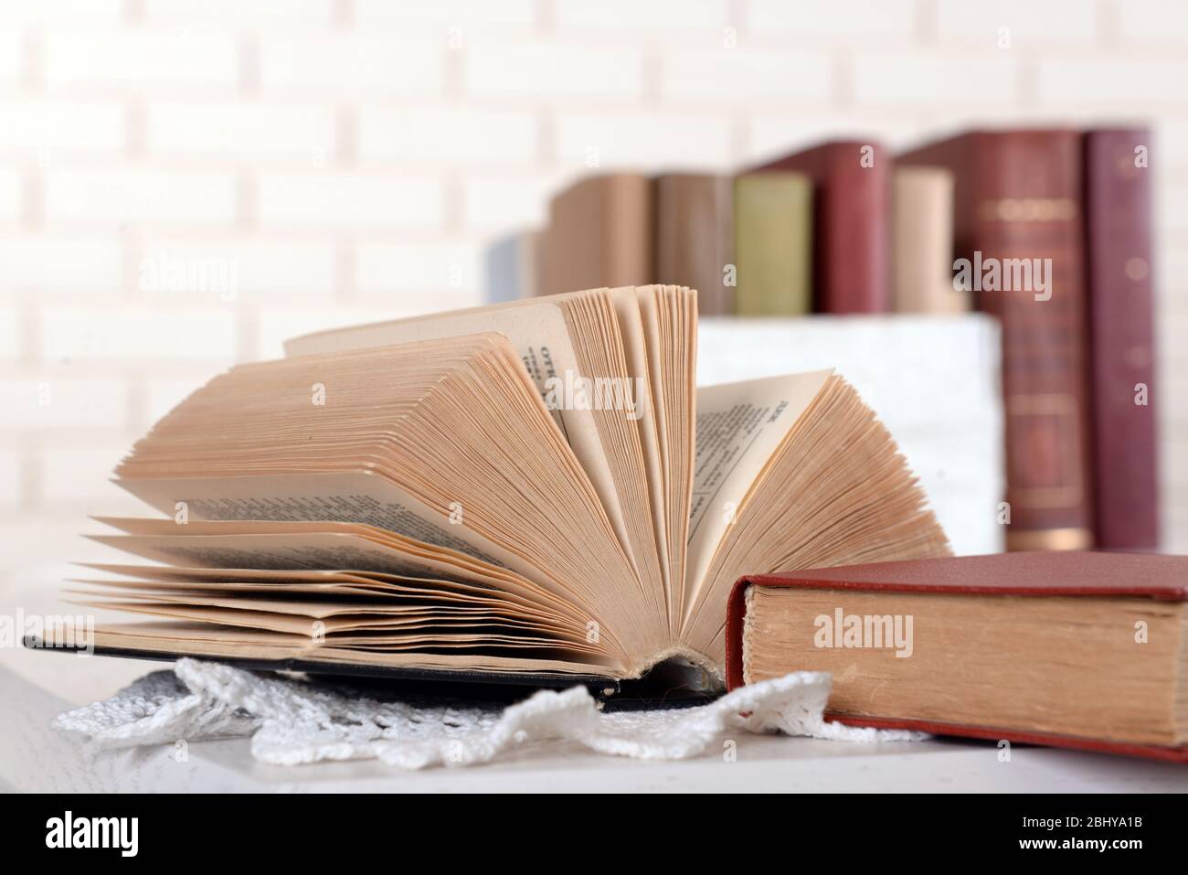 Heap of old books on brick wall background Stock Photo - Alamy