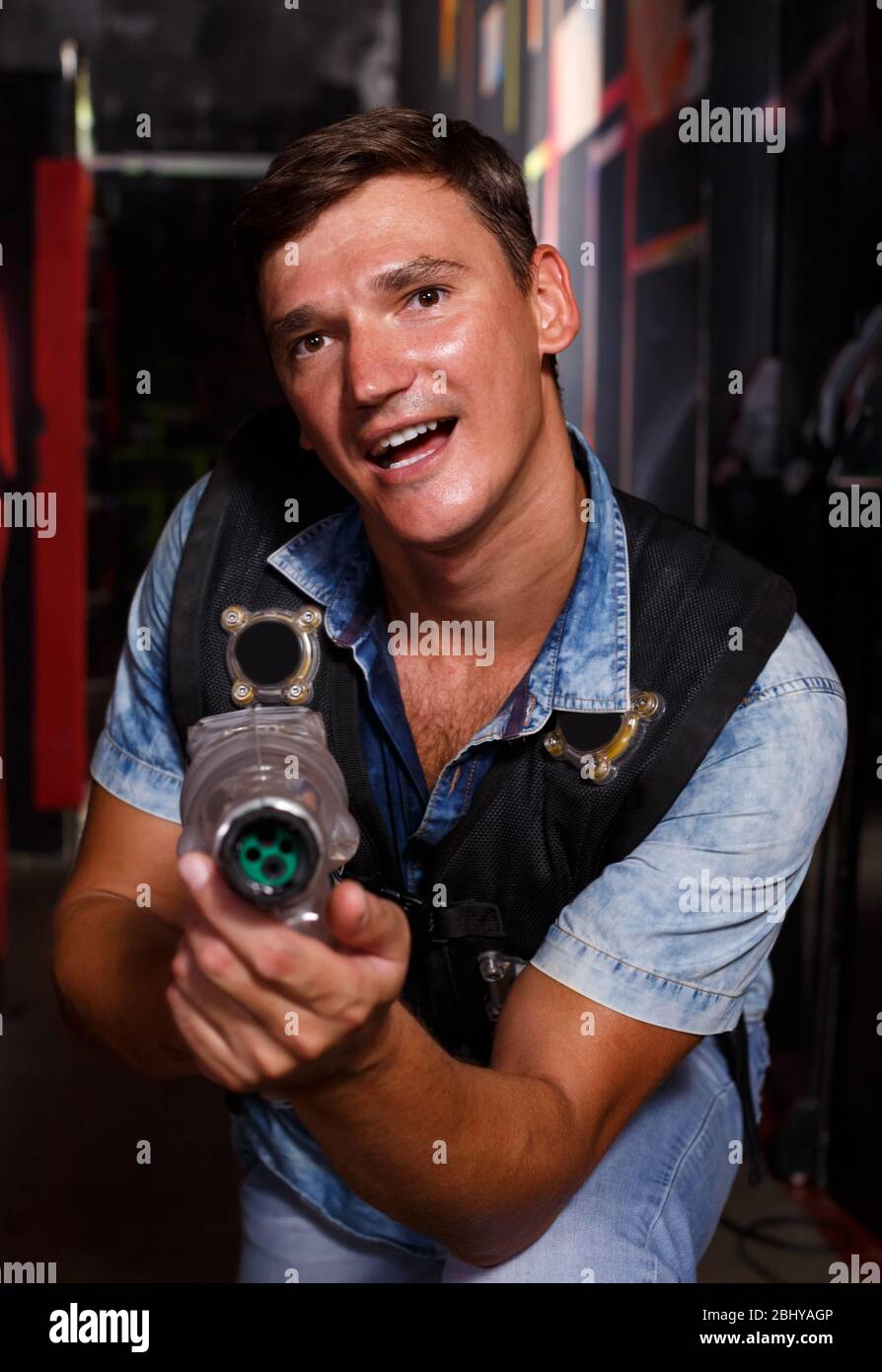 Emotional man holding colored laser gun and took aim during laser tag ...