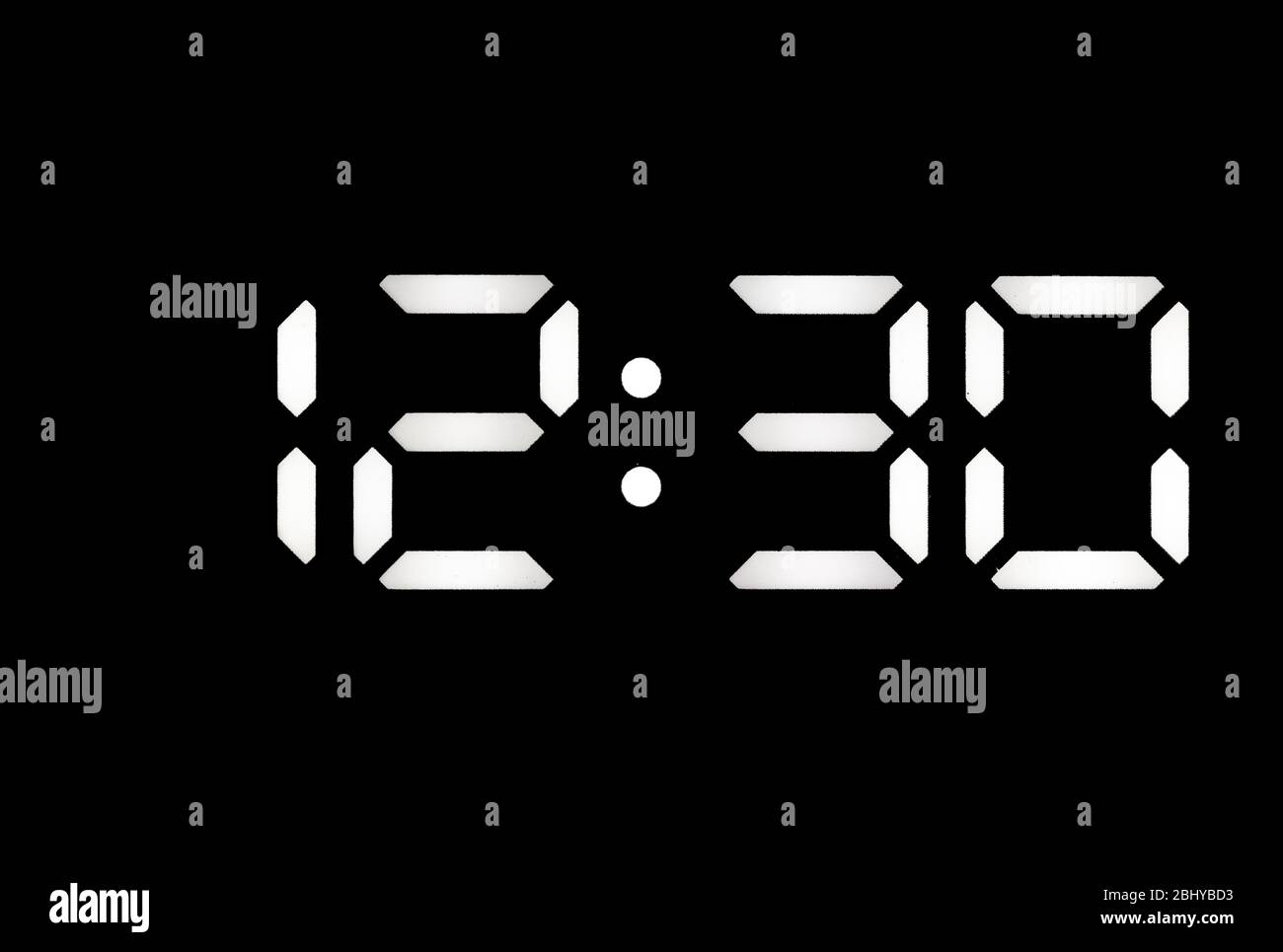 Real white led digital clock on a black background showing time 12:30 ...