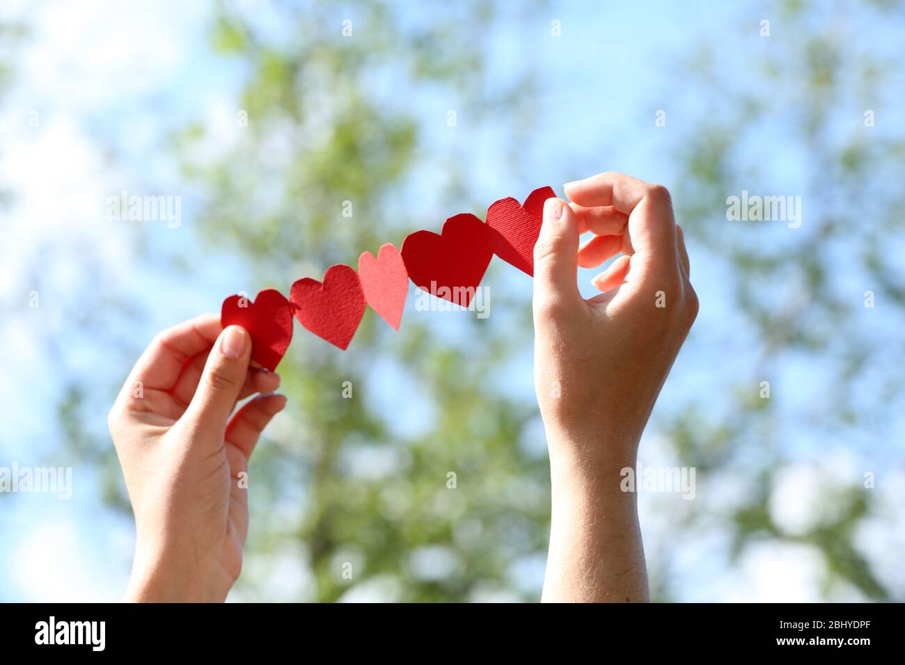 Female hands with chain of paper hearts over nature background Stock ...