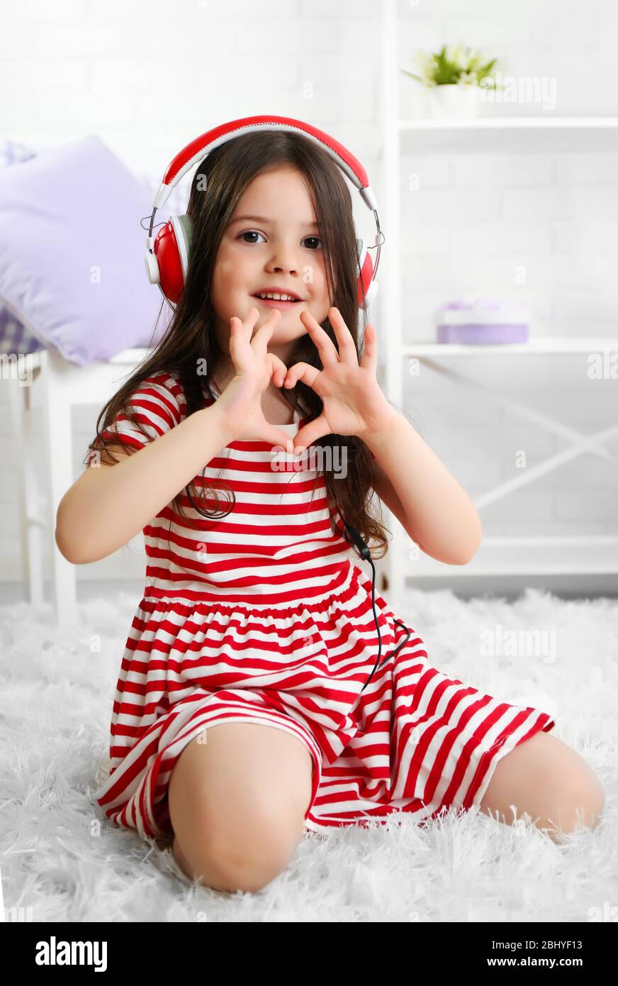 Beautiful little girl listening to music in room Stock Photo - Alamy