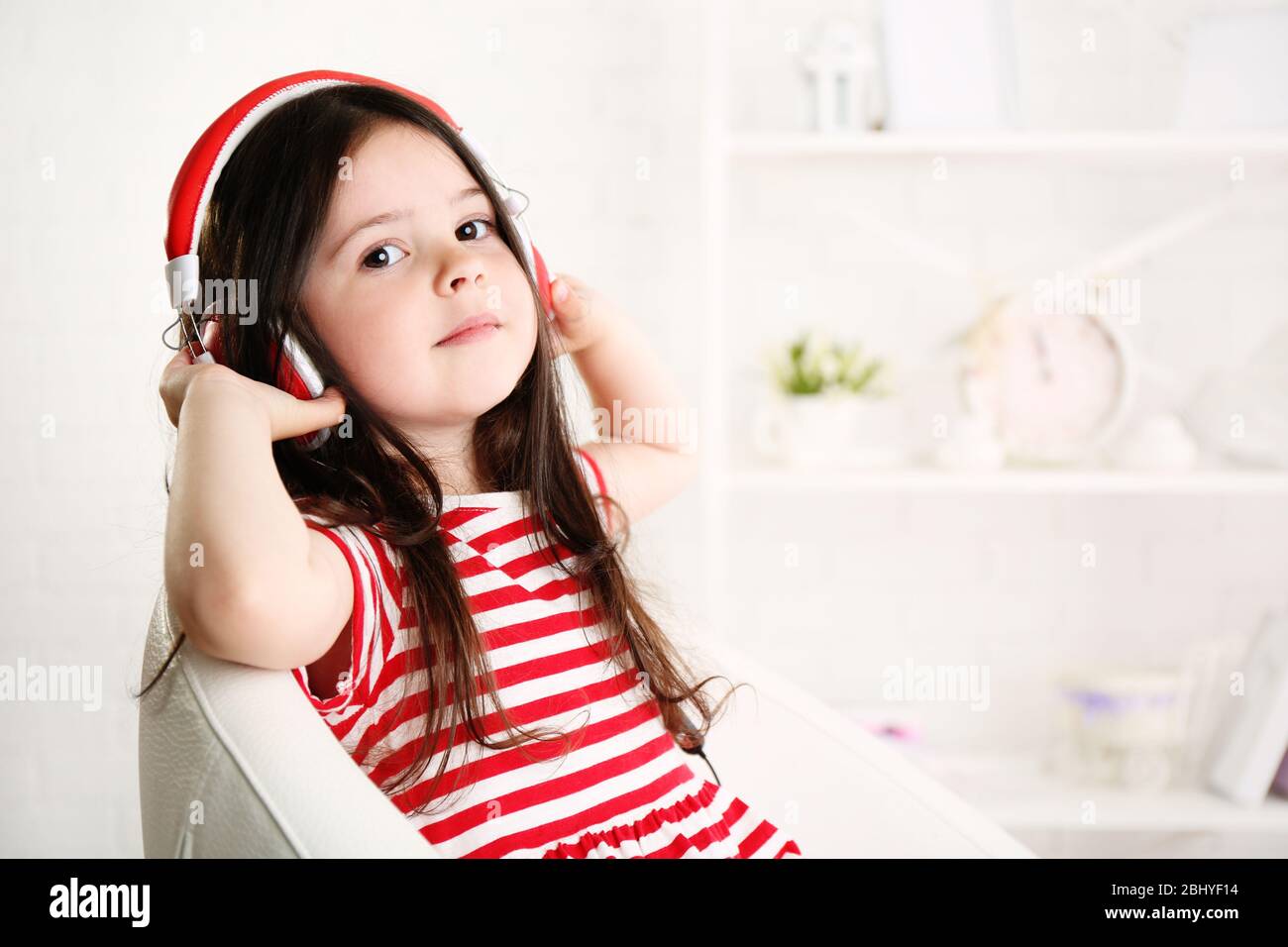 Beautiful little girl listening to music in room Stock Photo - Alamy