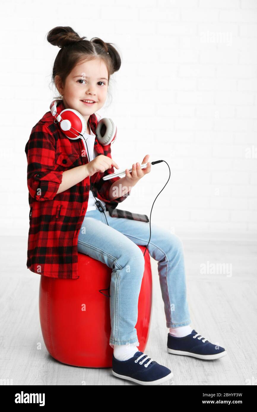 Beautiful little girl with headphones in room Stock Photo - Alamy