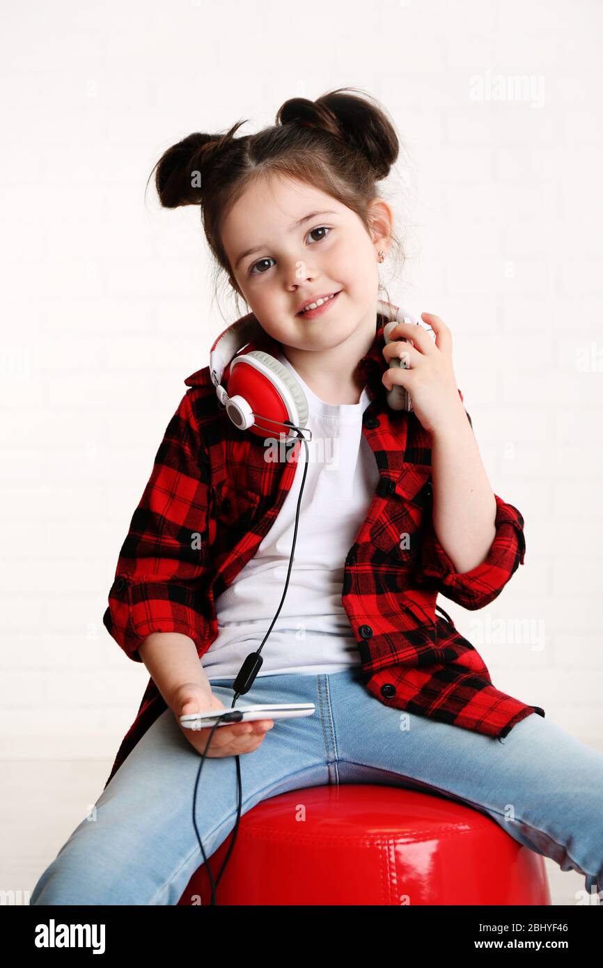 Beautiful little girl with headphones in room Stock Photo - Alamy