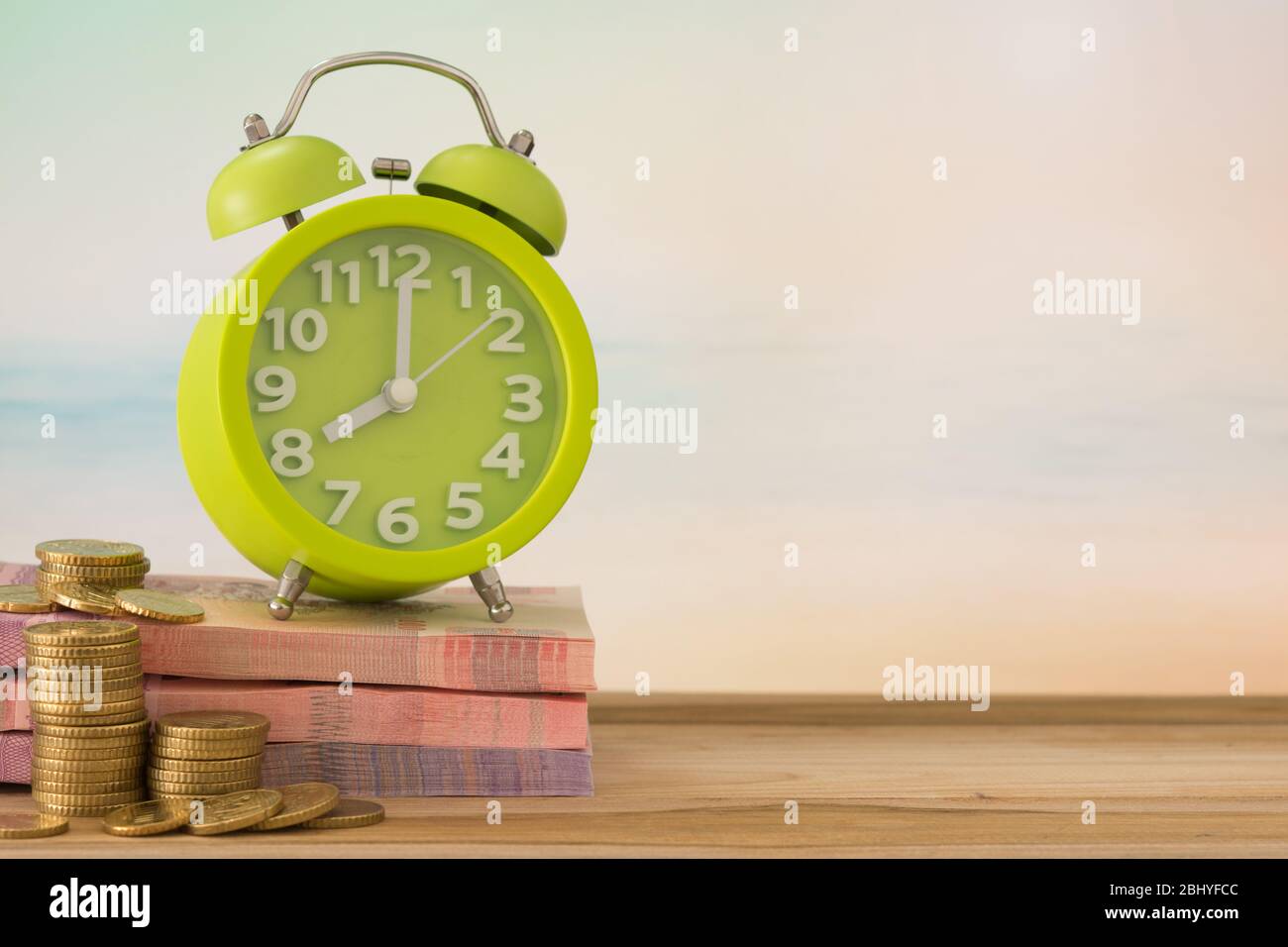 clock with money on desk in nature background. concept of time is money ...