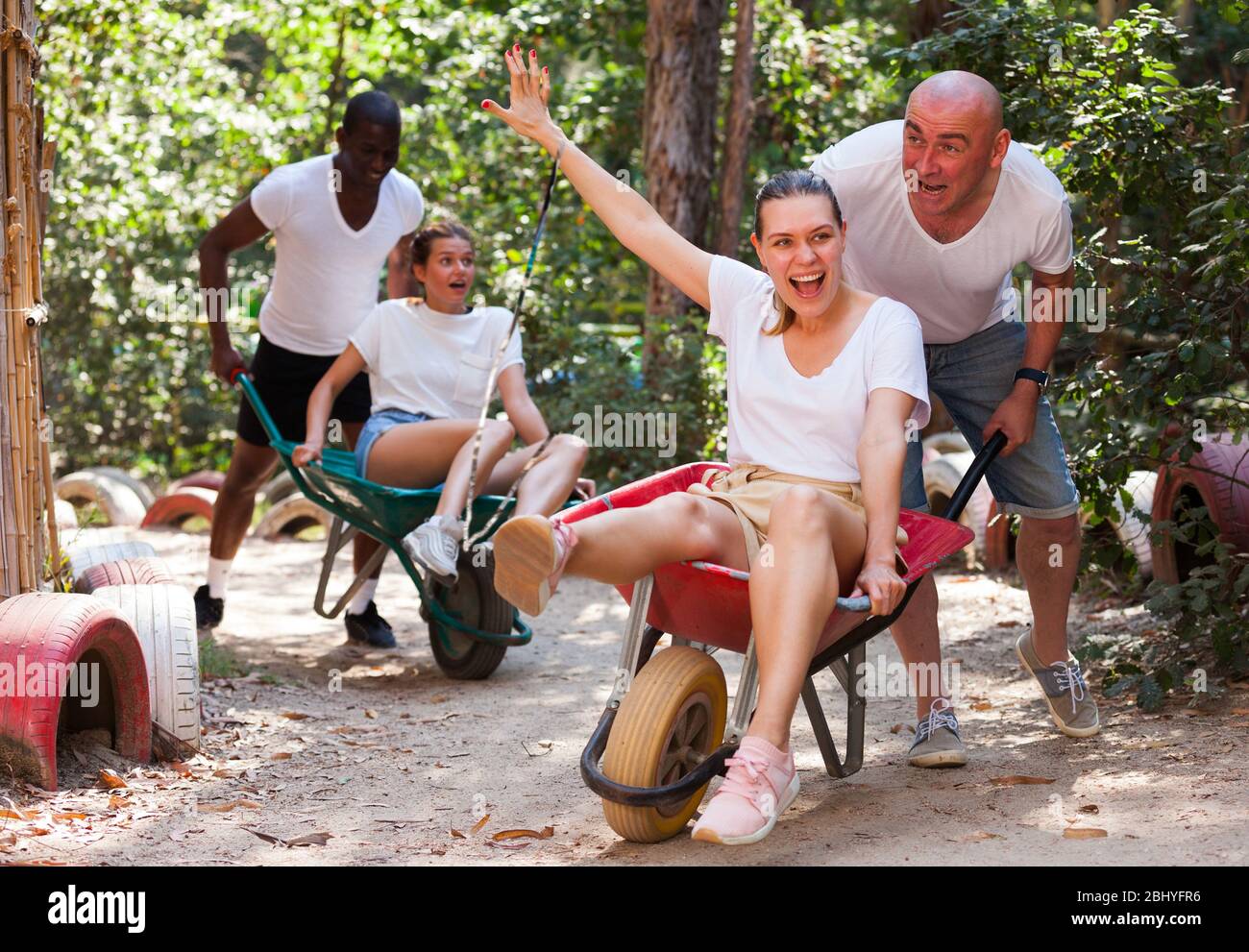Group of people doing exercise with wheelbarrows together at adventure ...