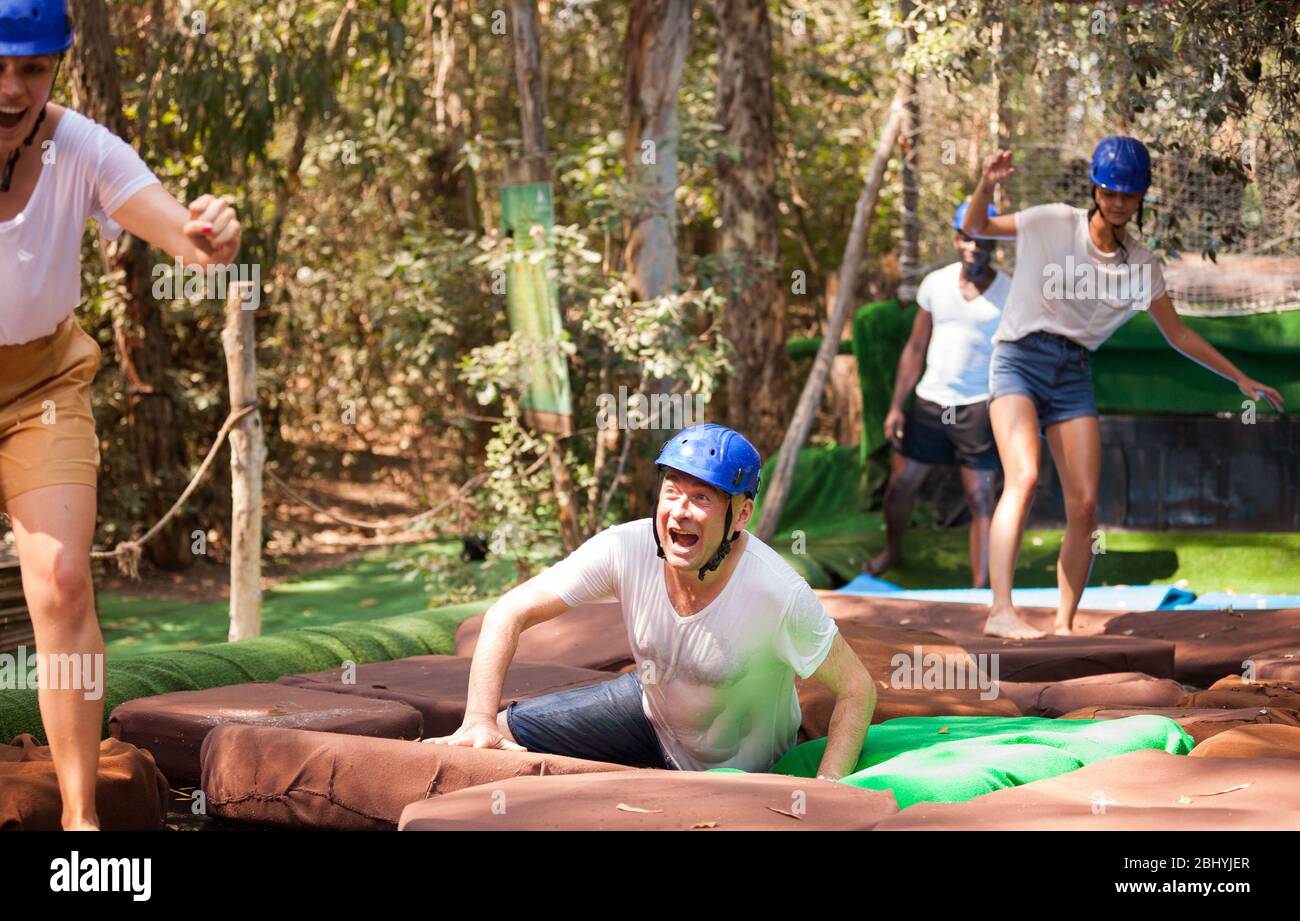 Excited men and women passing water obstacles in adventure park Stock ...