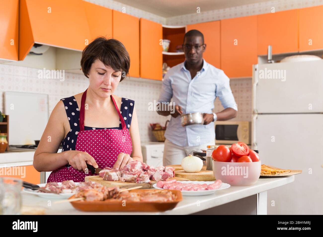 Positive couple making meat dinner together at home Stock Photo - Alamy