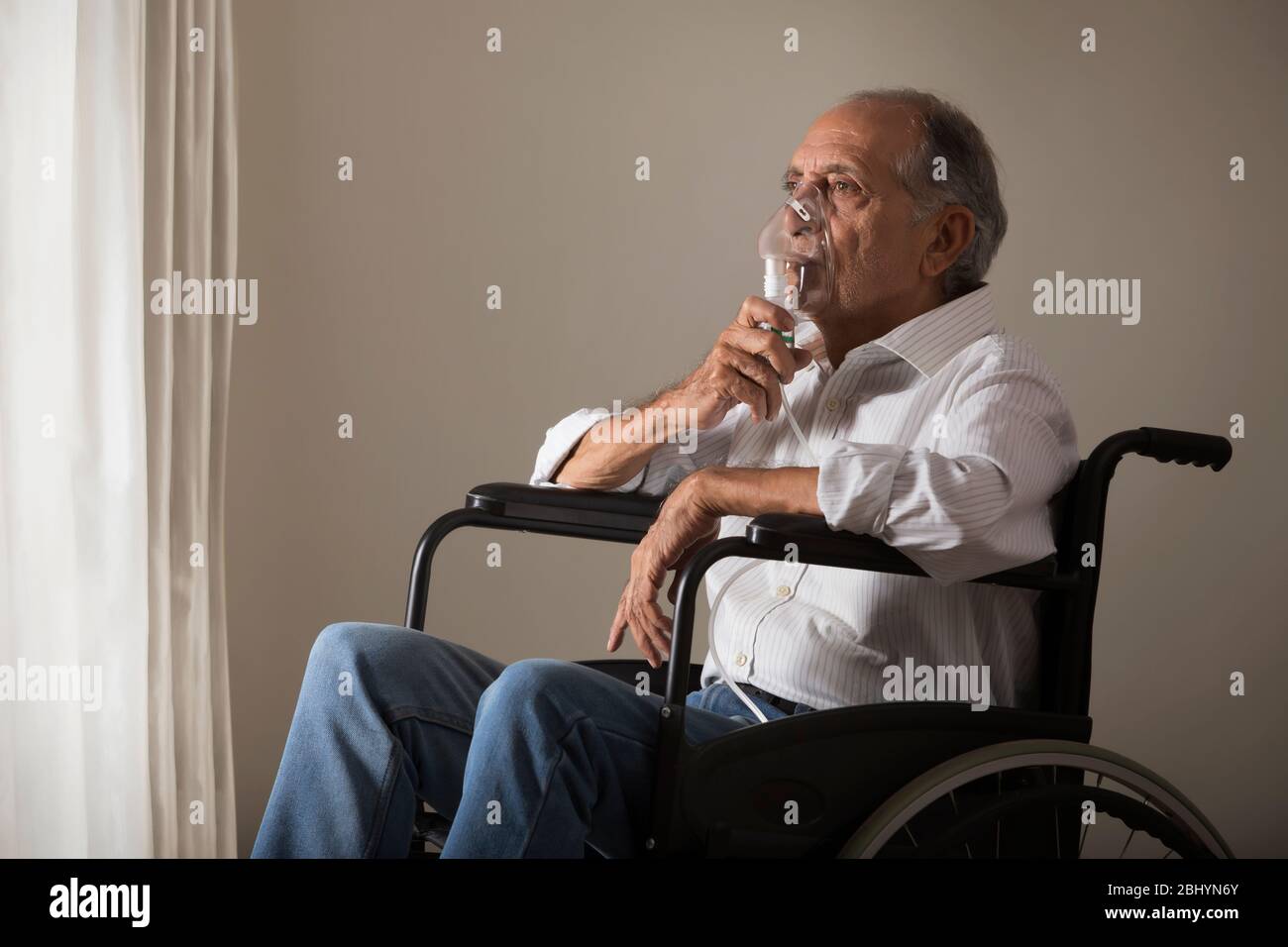 Senior man sitting on a wheelchair with an oxygen mask. (Health and ...