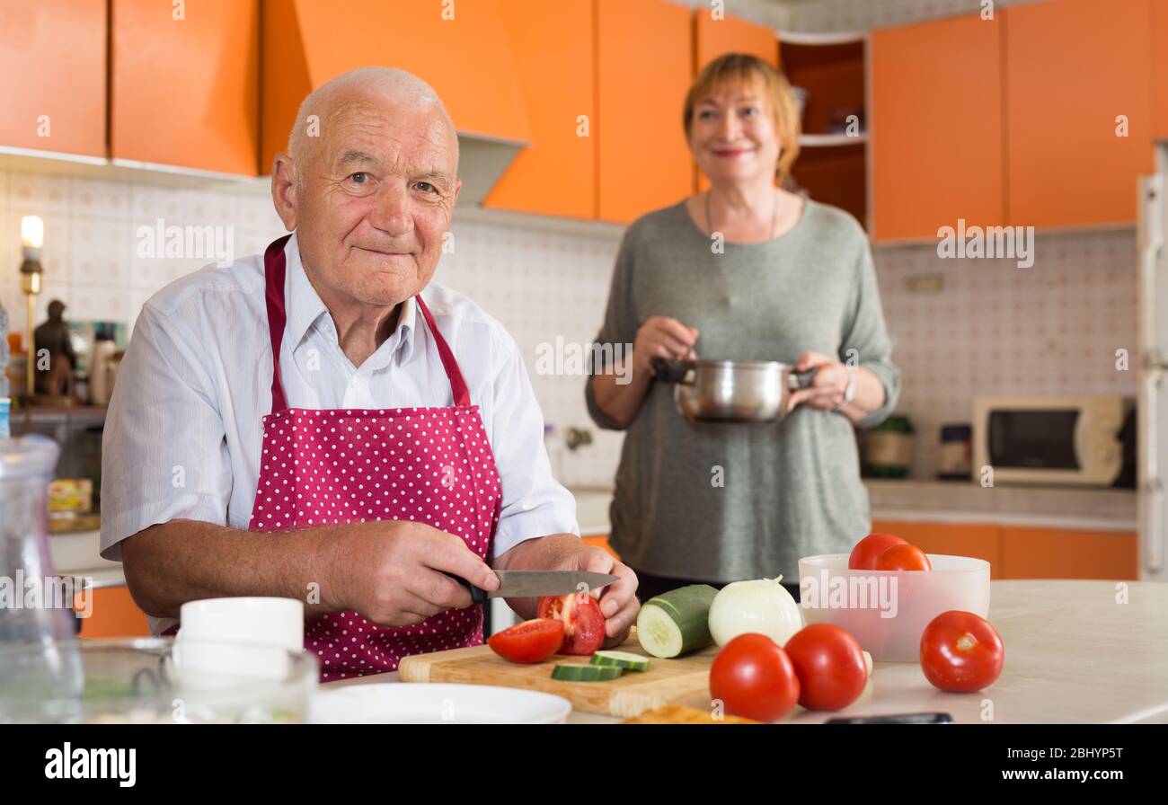 Cheerful senior couple cooking together in kitchen Stock Photo - Alamy