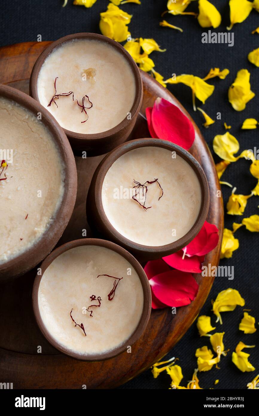 Kullads of mishti dahi kept on a wooden plate with petals around it ...