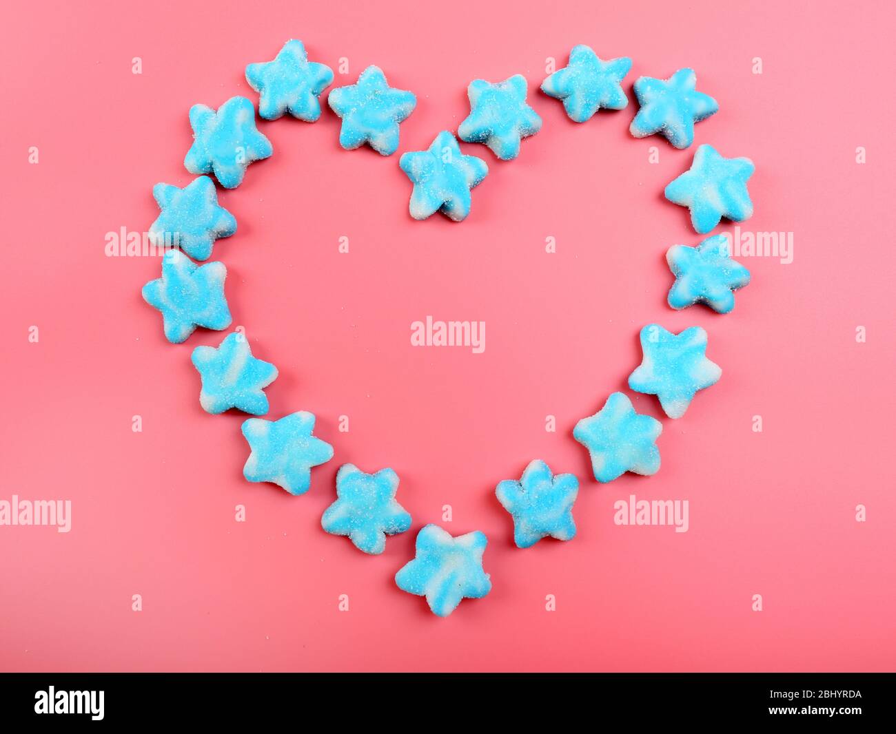 Blue candies heart shaped on pink background Stock Photo - Alamy