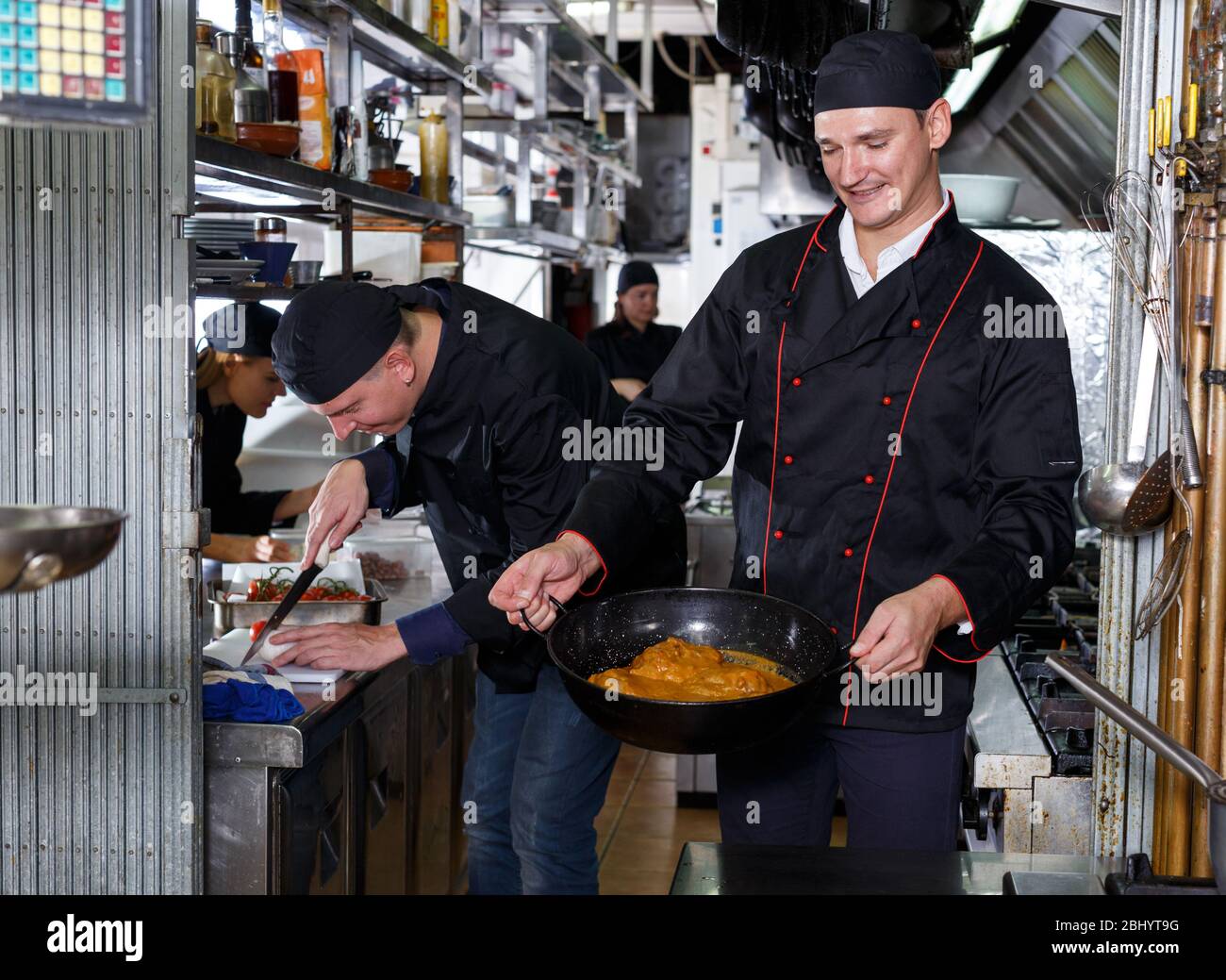 Positive cooks in process of working in kitchen of restaurant Stock ...