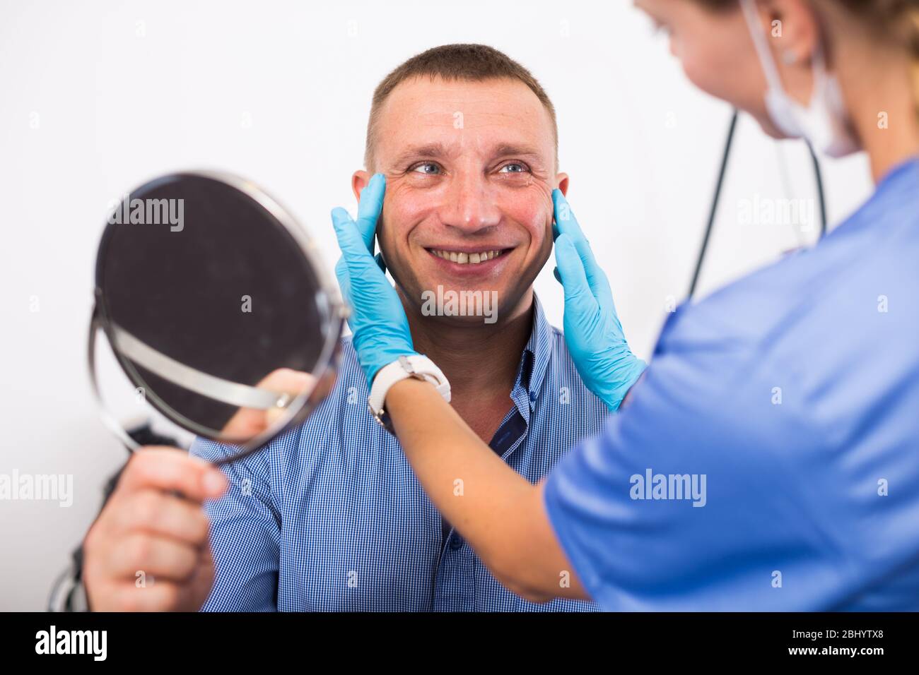 Woman doctor is examining patient behind mirror before the procedure in ...