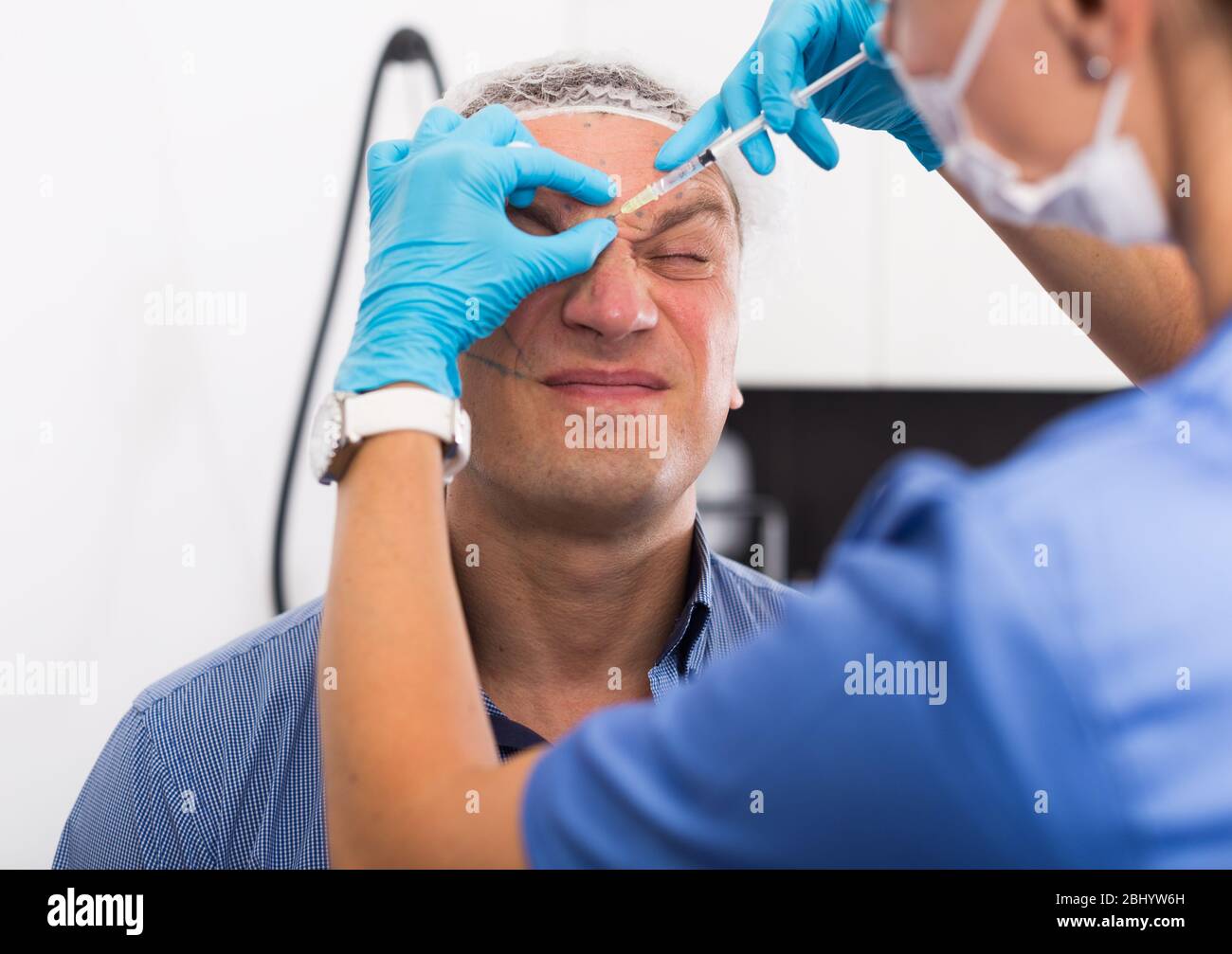 Female doctor is doing injection to patient in skin of face in estetic ...