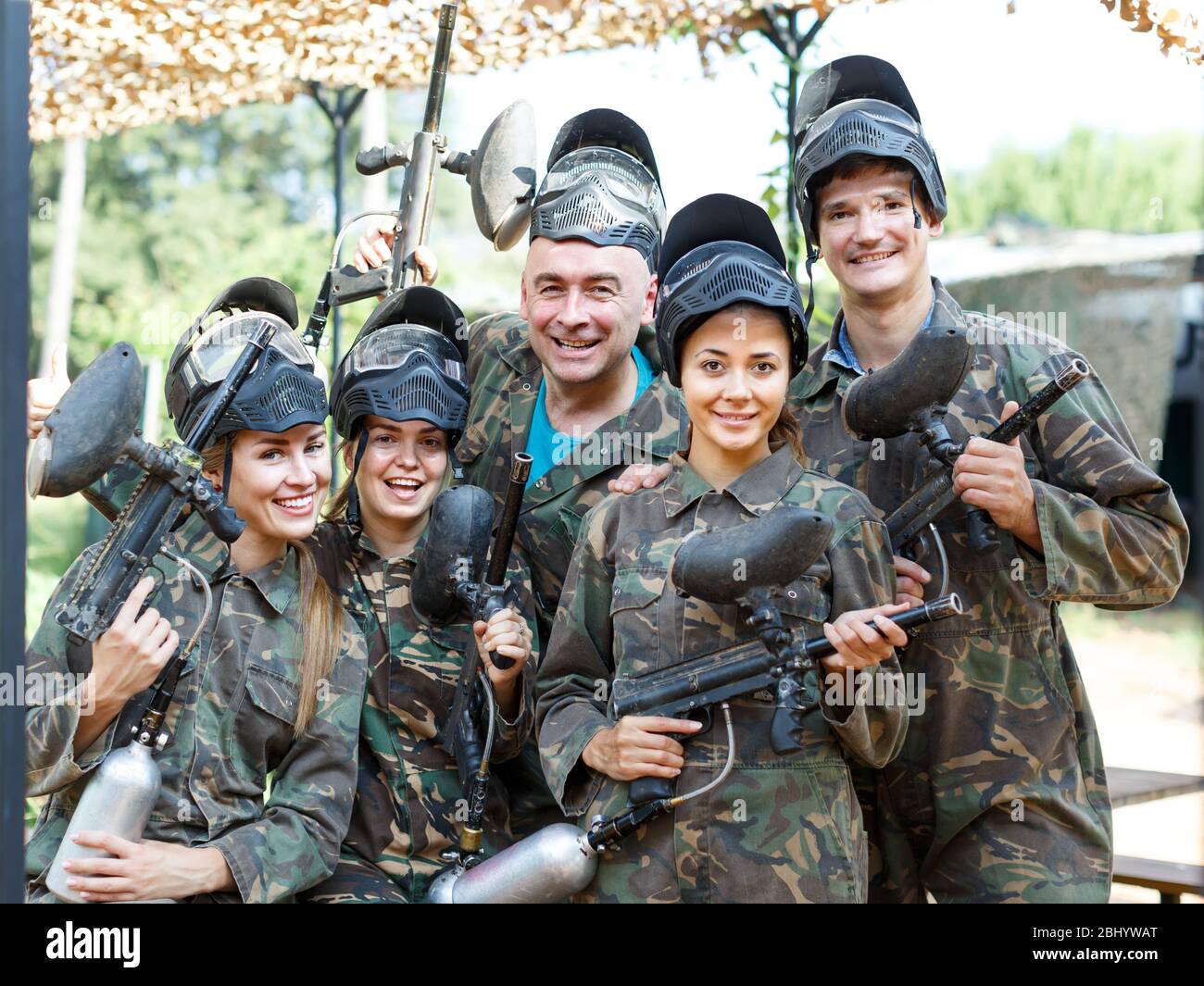 Portrait of team of paintball players with marker guns ready for game ...