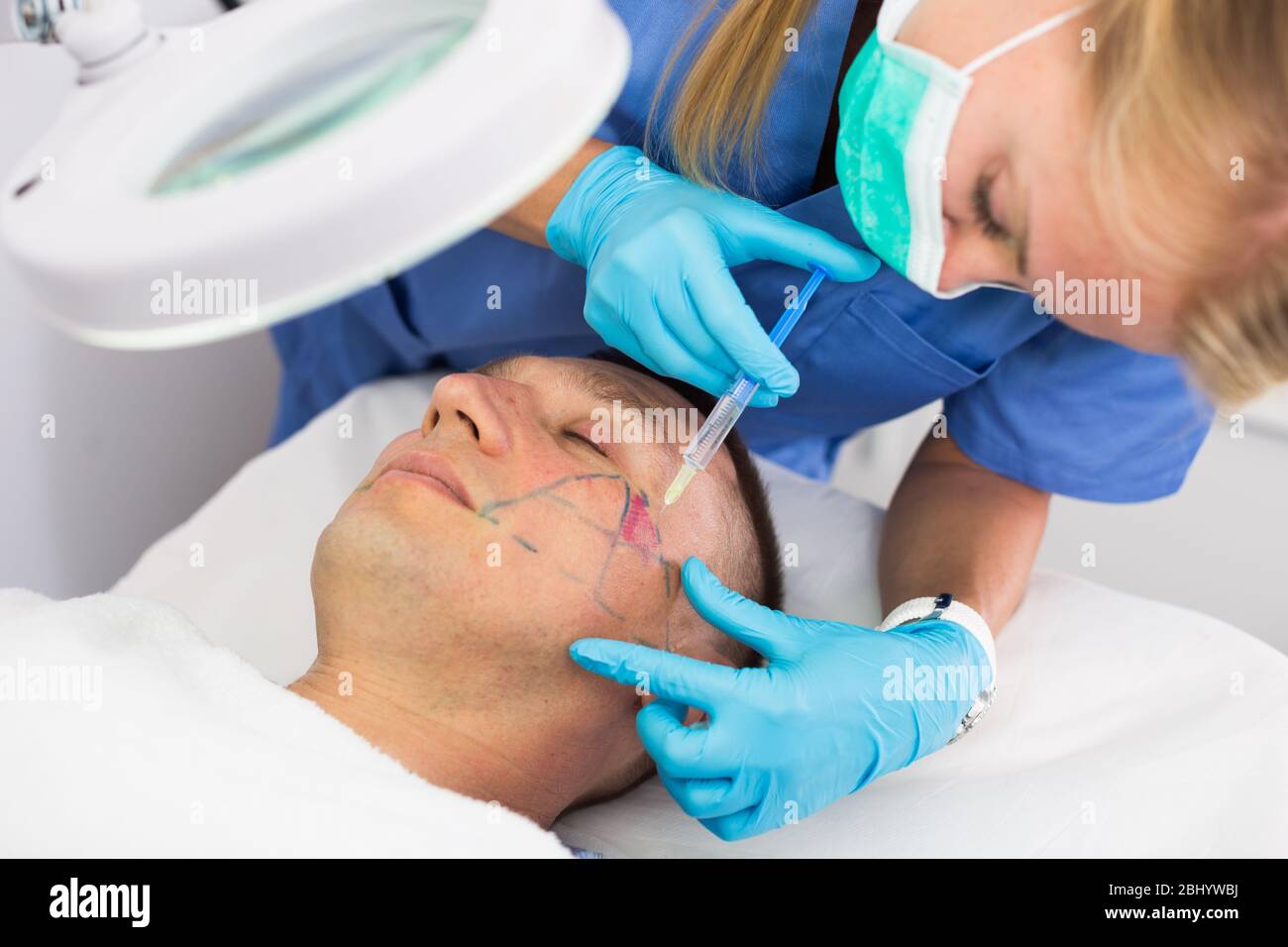 Female doctor is doing injection to patient in skin of face in estetic ...