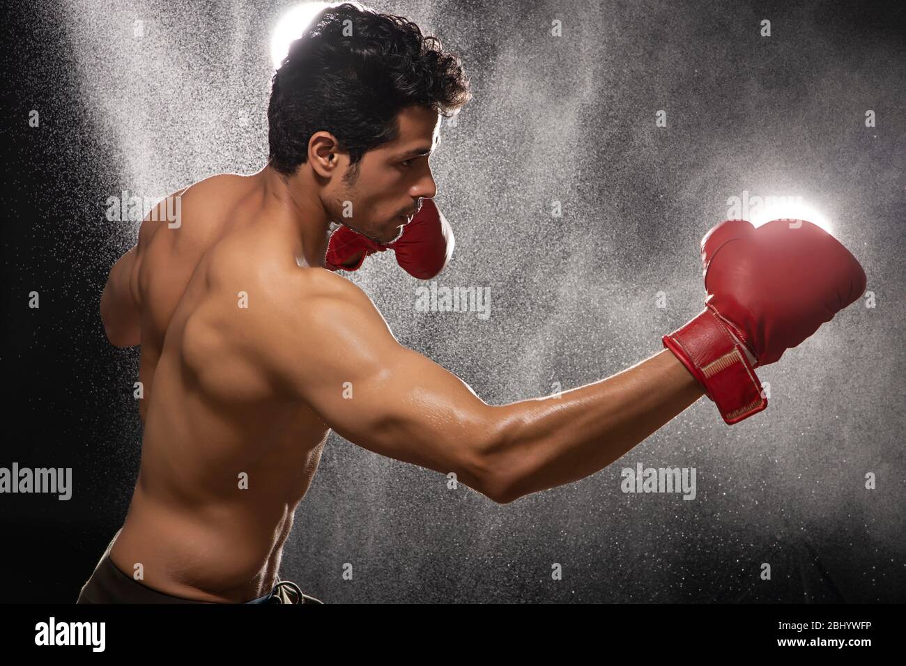 Man throwing punch in the air while wearing boxing gloves in front of a ...