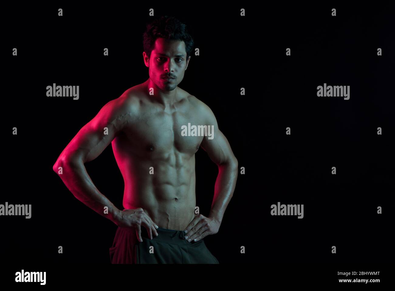 Man flexing his muscles in front of a dark background Stock Photo - Alamy