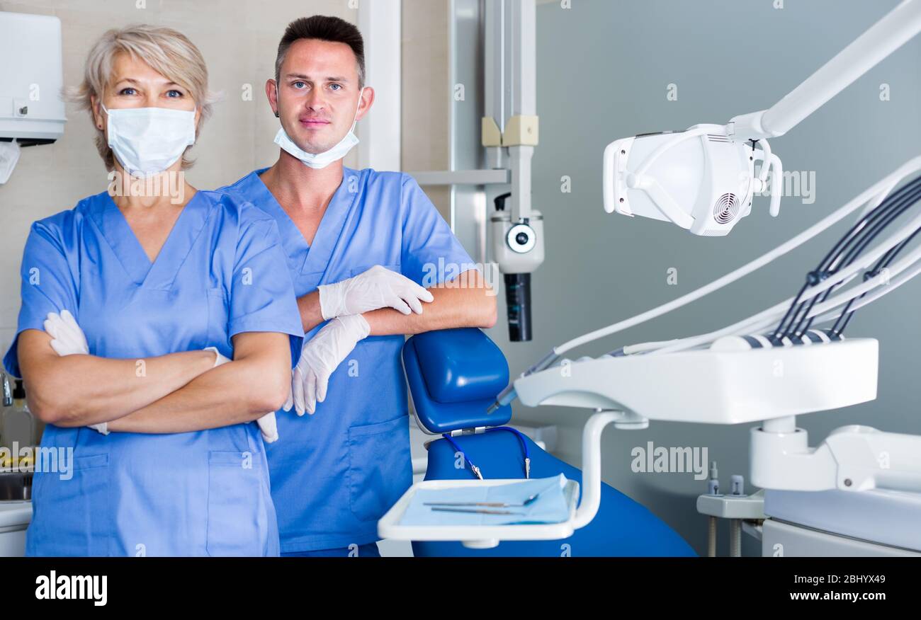 Portrait of two professional smiling dentists standing in modern ...