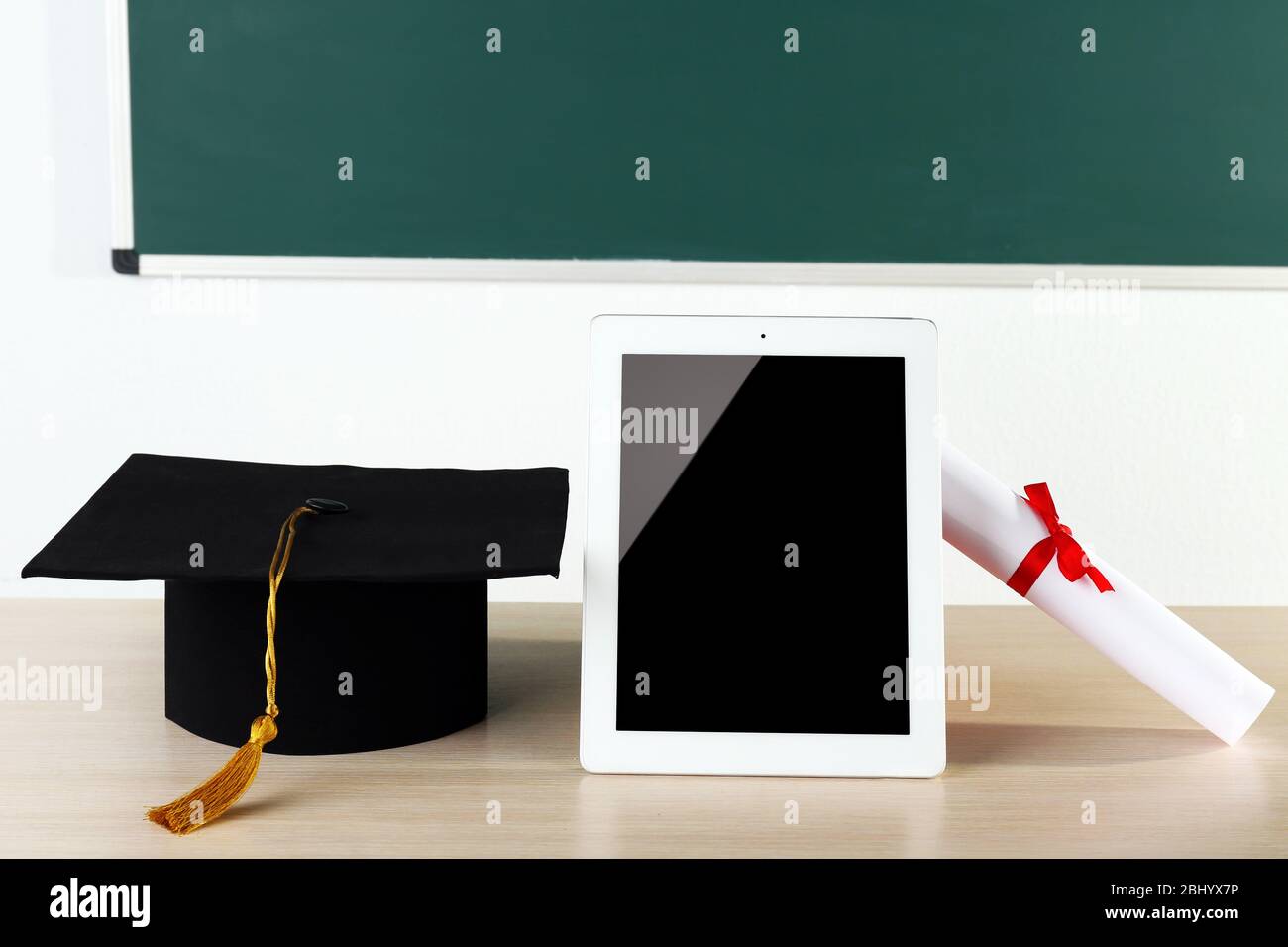 Graduation cap with tablet and diploma on table in class Stock Photo ...