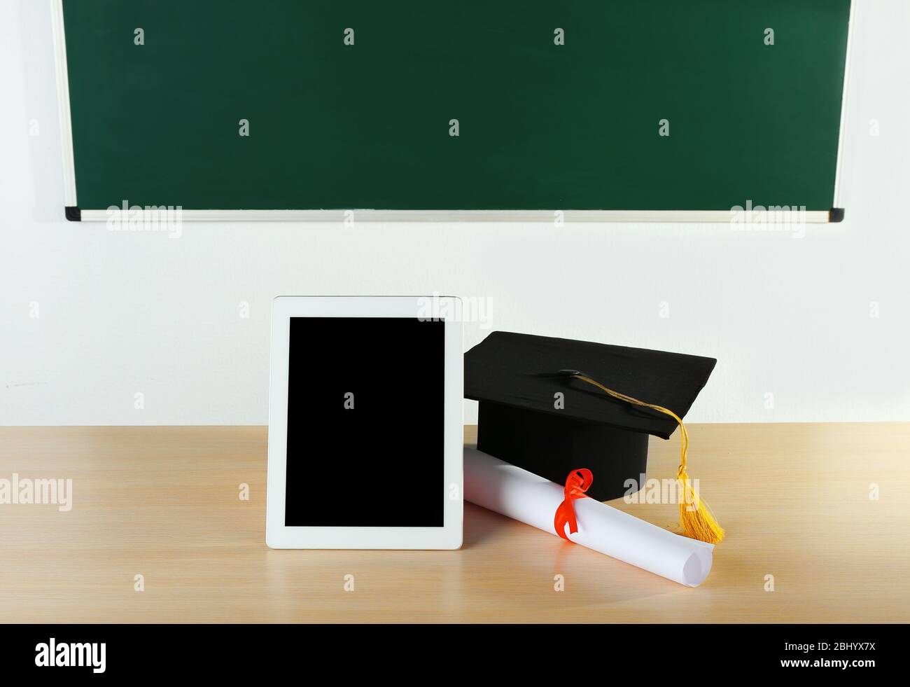 Graduation cap with tablet and diploma on table in class Stock Photo ...