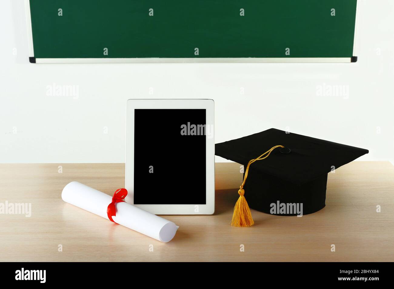 Graduation cap with tablet and diploma on table in class Stock Photo ...