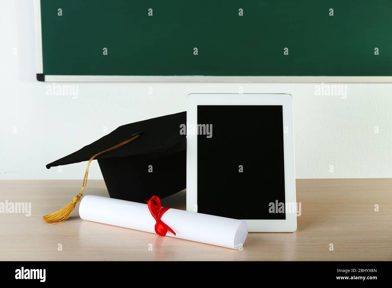 Graduation cap with tablet and diploma on table in class Stock Photo ...