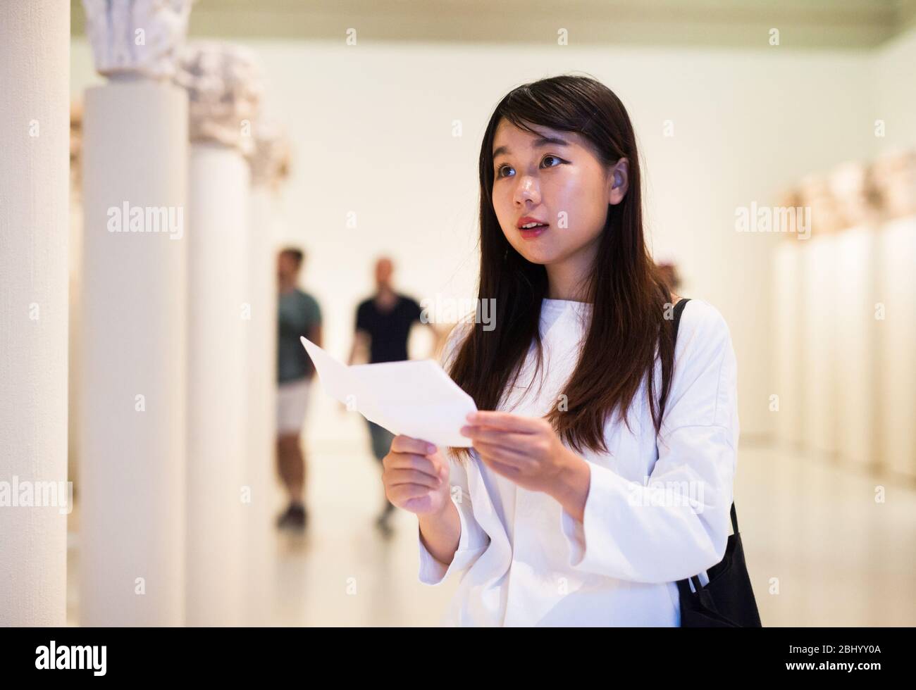 Portrait of young chinese woman with guide looking at exhibition in ...