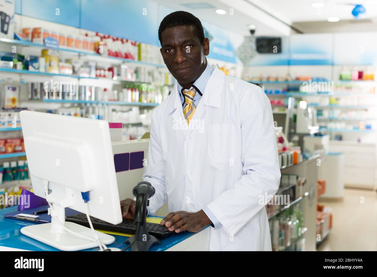 Experienced African American man pharmacist working on computer in ...