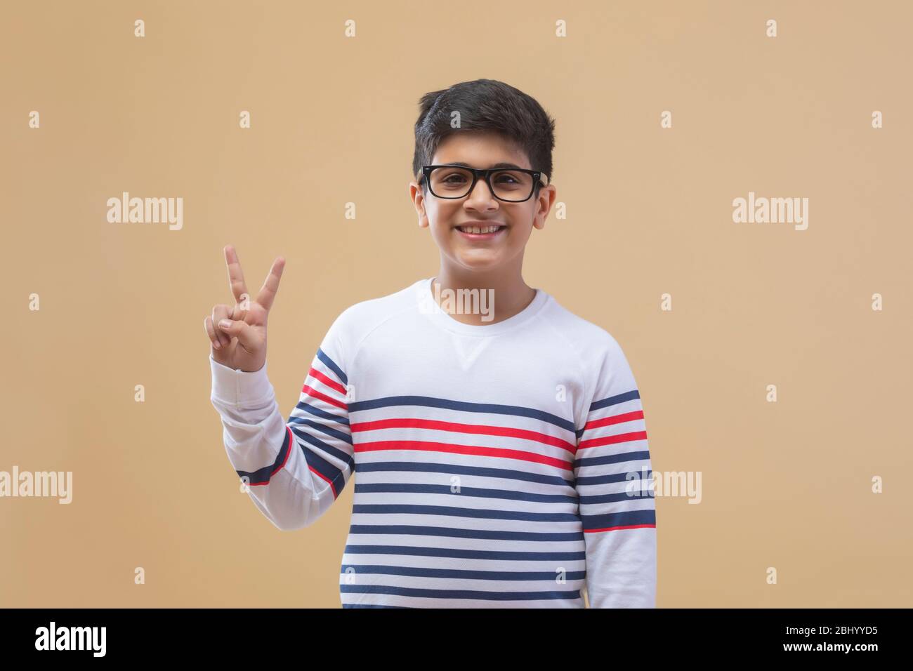 Portrait Of boy showing a victory sign Against color background Stock ...