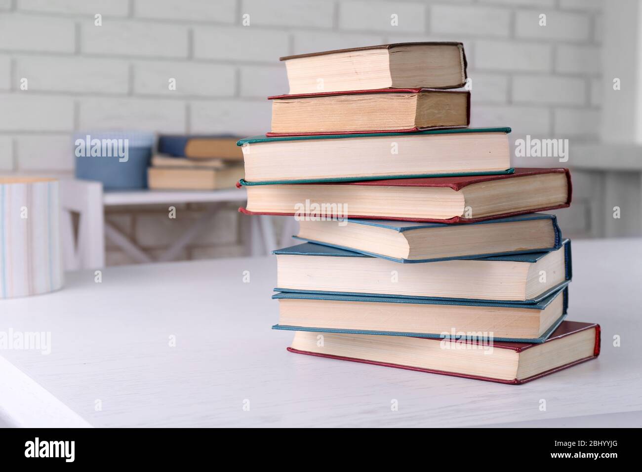 Stack of books on light surface, om bricks wall background Stock Photo ...