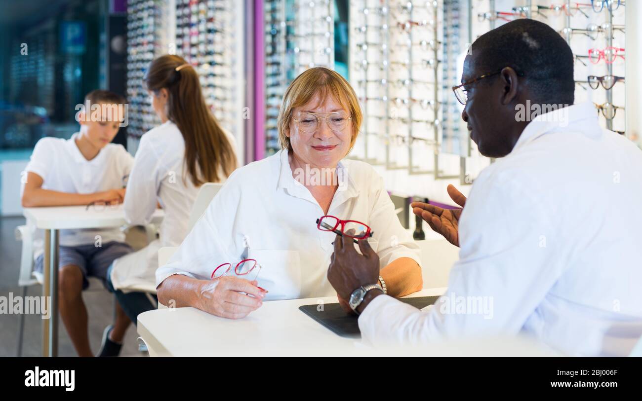 Senior woman looking glasses frames, ophthalmologist helping Stock ...
