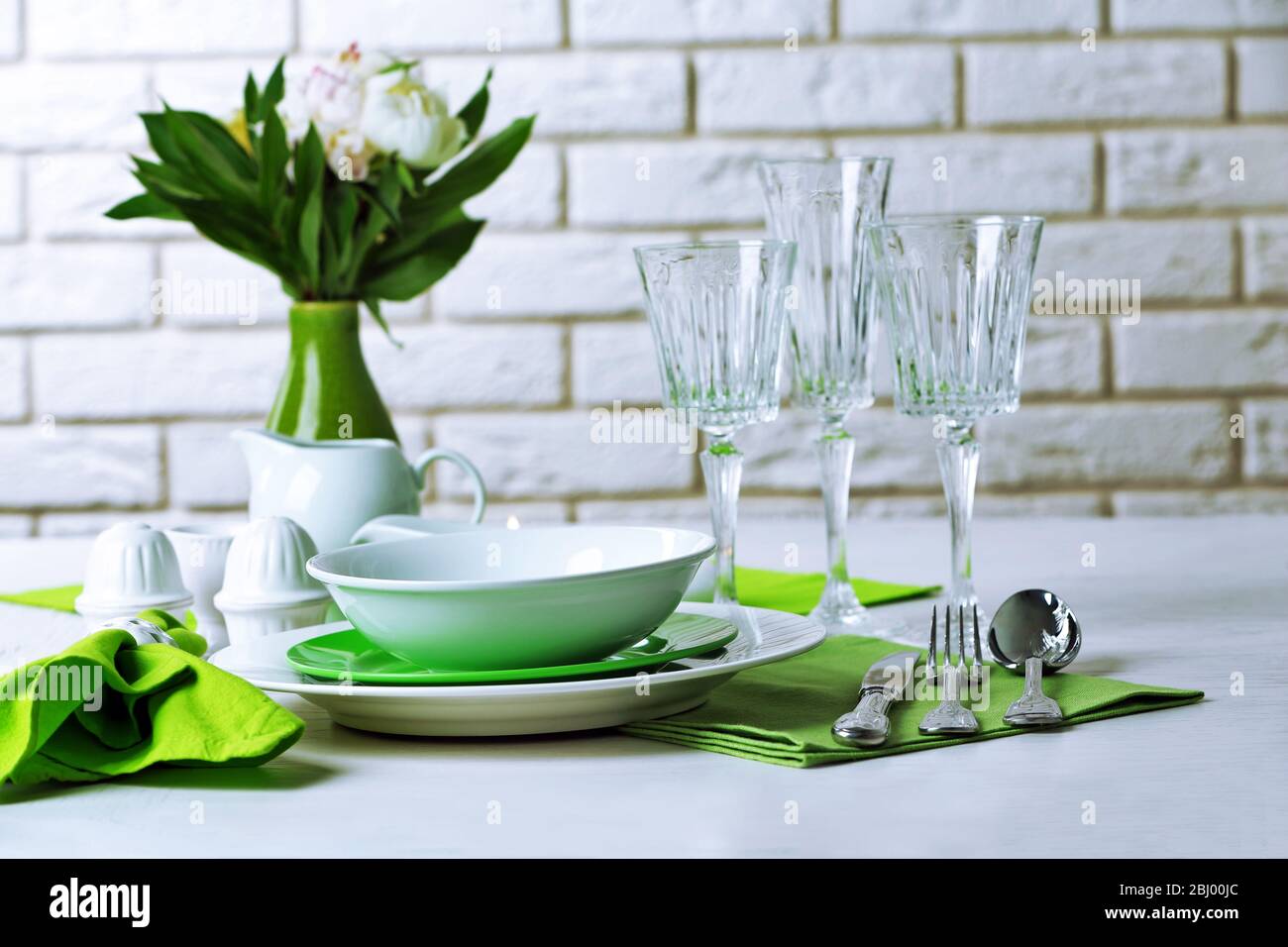 Beautiful table setting with flowers in vase on brick wall background ...