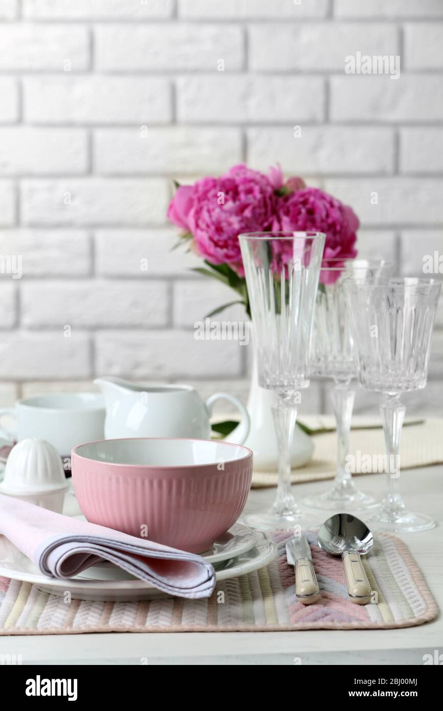 Beautiful table setting with flowers in vase on brick wall background ...