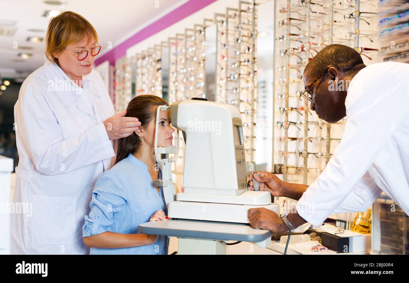 African-American optometrist with aged female assistant testing ...
