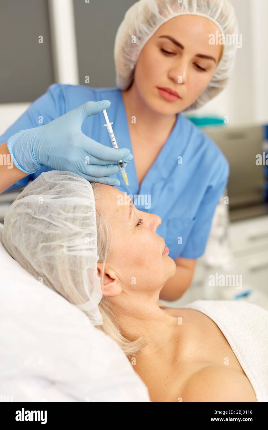 Senior woman getting injection for facial rejuvenation procedure in ...