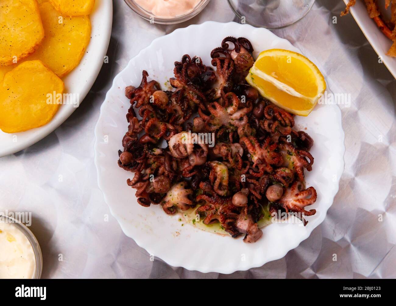 Marinated mini calamari with lemon slice on white platter Stock Photo ...