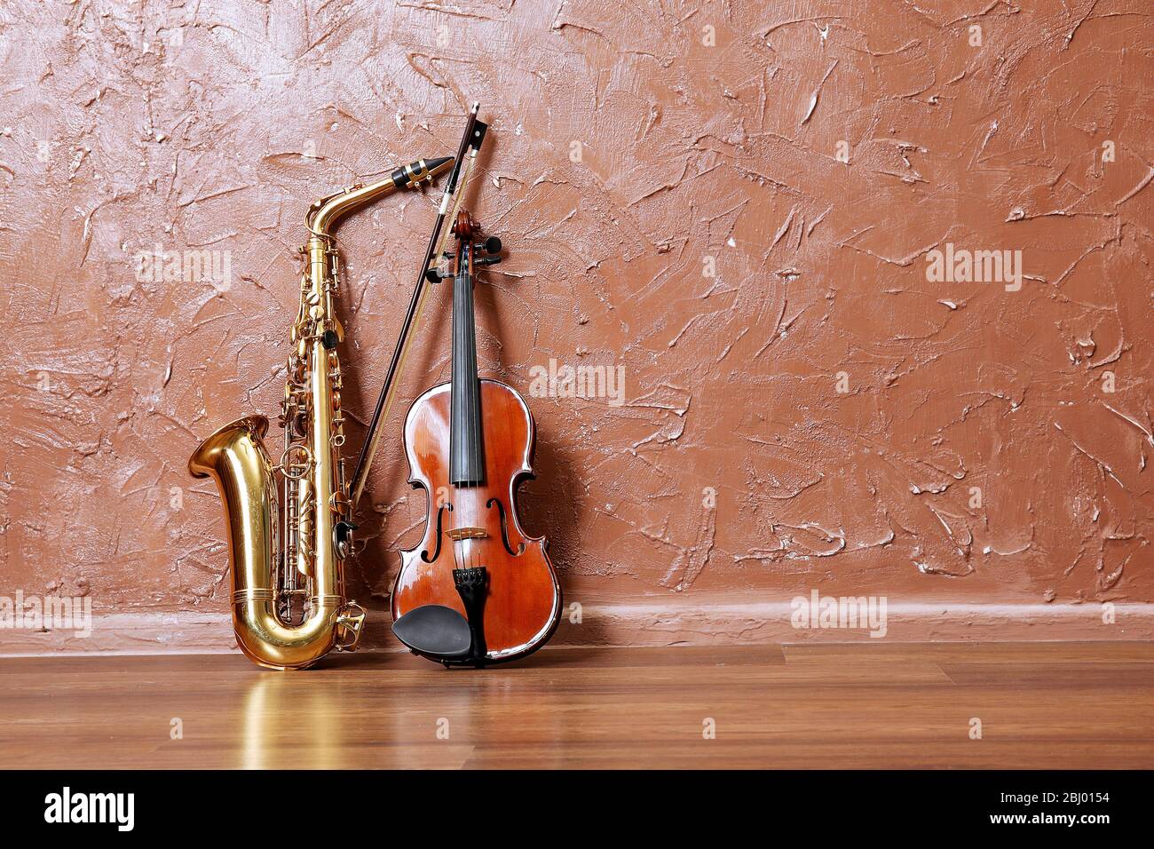 Saxophone and violin on brown wall background Stock Photo - Alamy