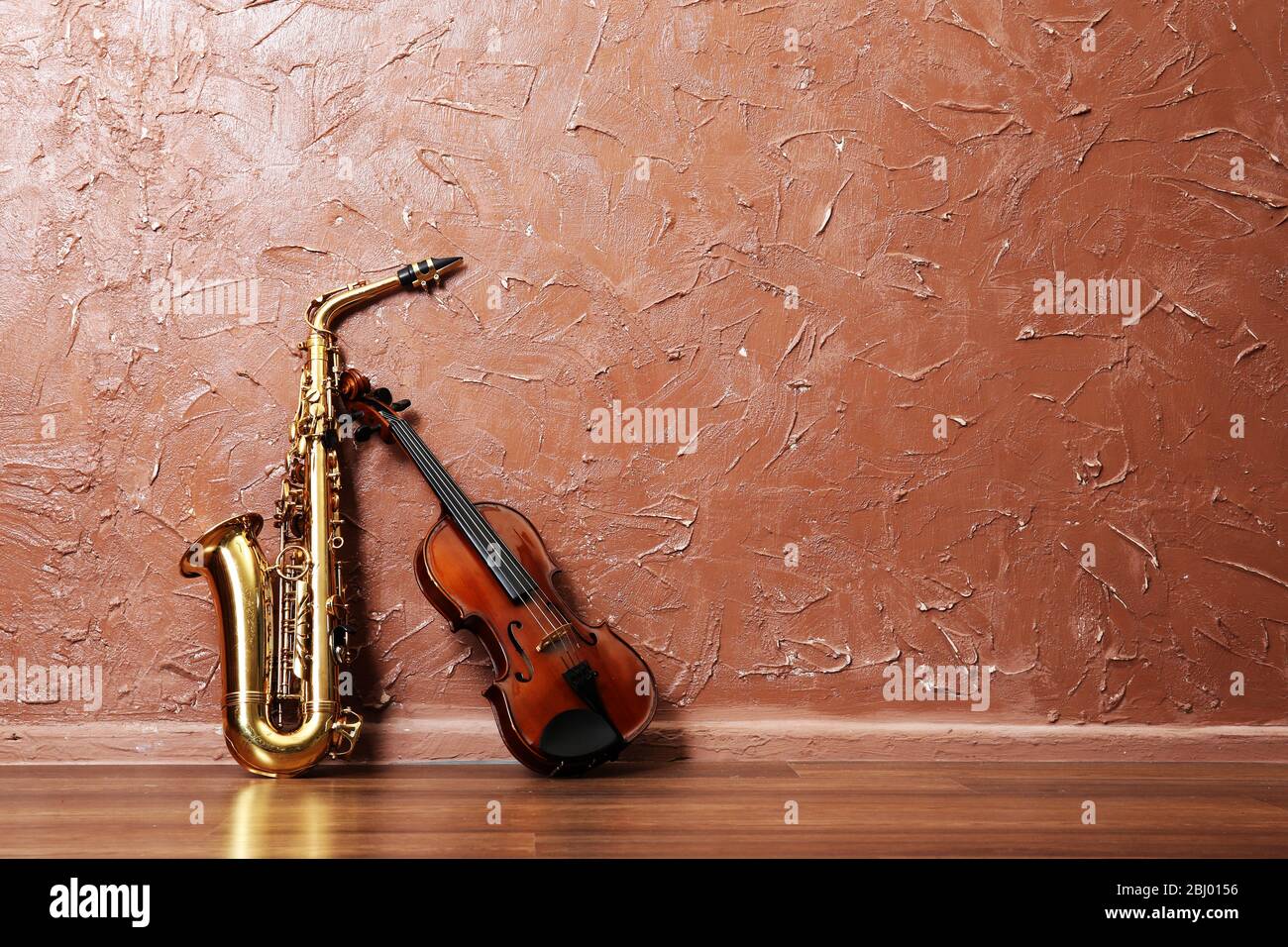 Saxophone and violin on brown wall background Stock Photo - Alamy